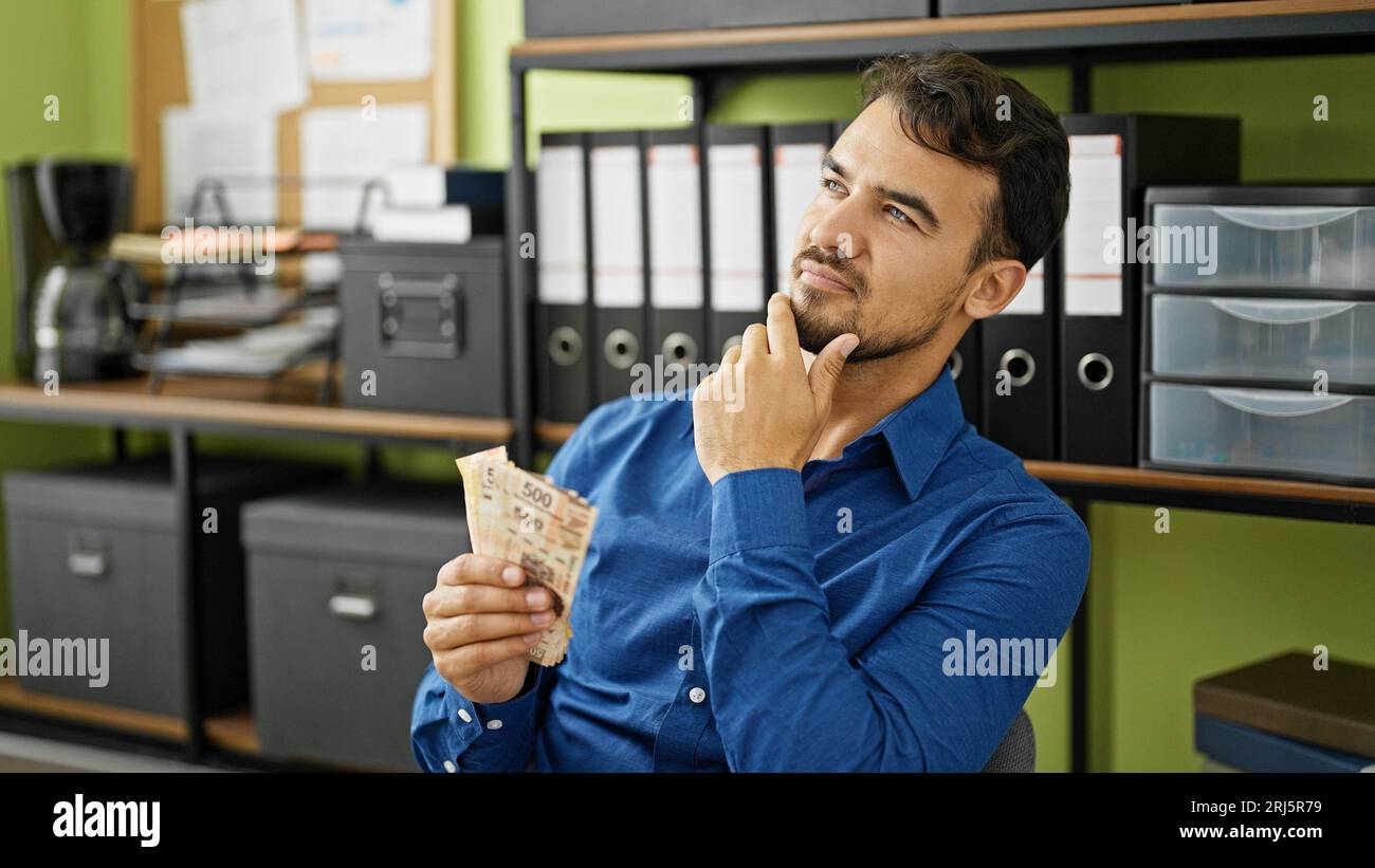 Young hispanic man business worker counting mexican pesos banknotes at ...