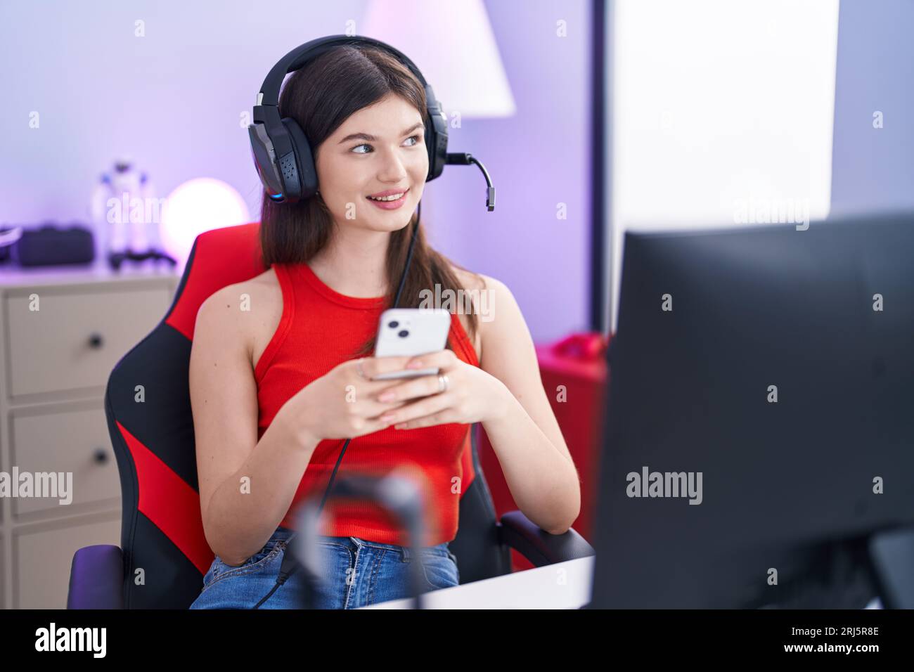 Young caucasian woman streamer using computer and smartphone at gaming ...