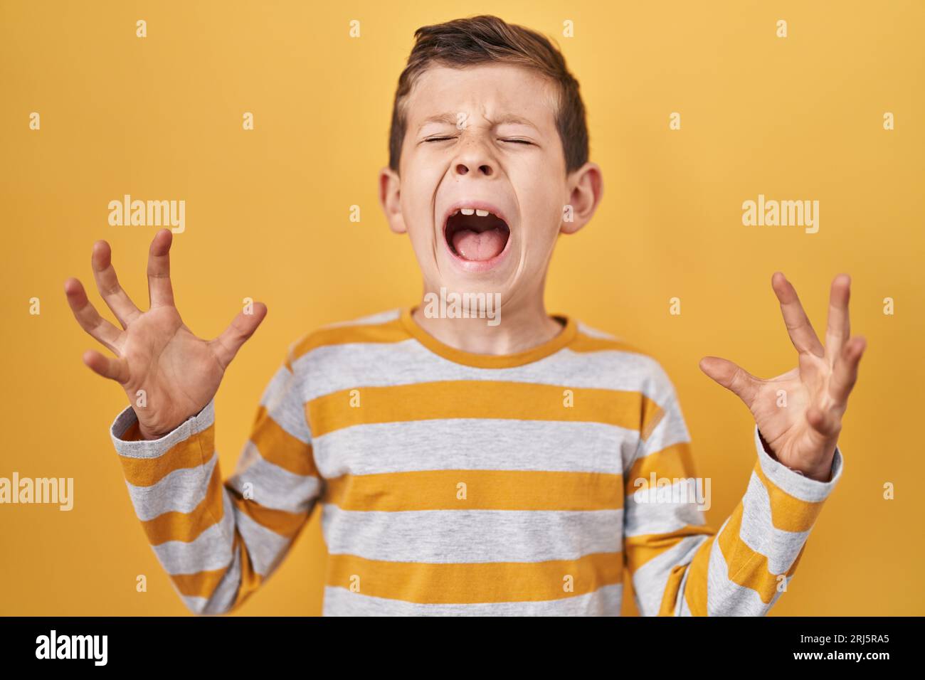 Young caucasian kid standing over yellow background celebrating mad and ...