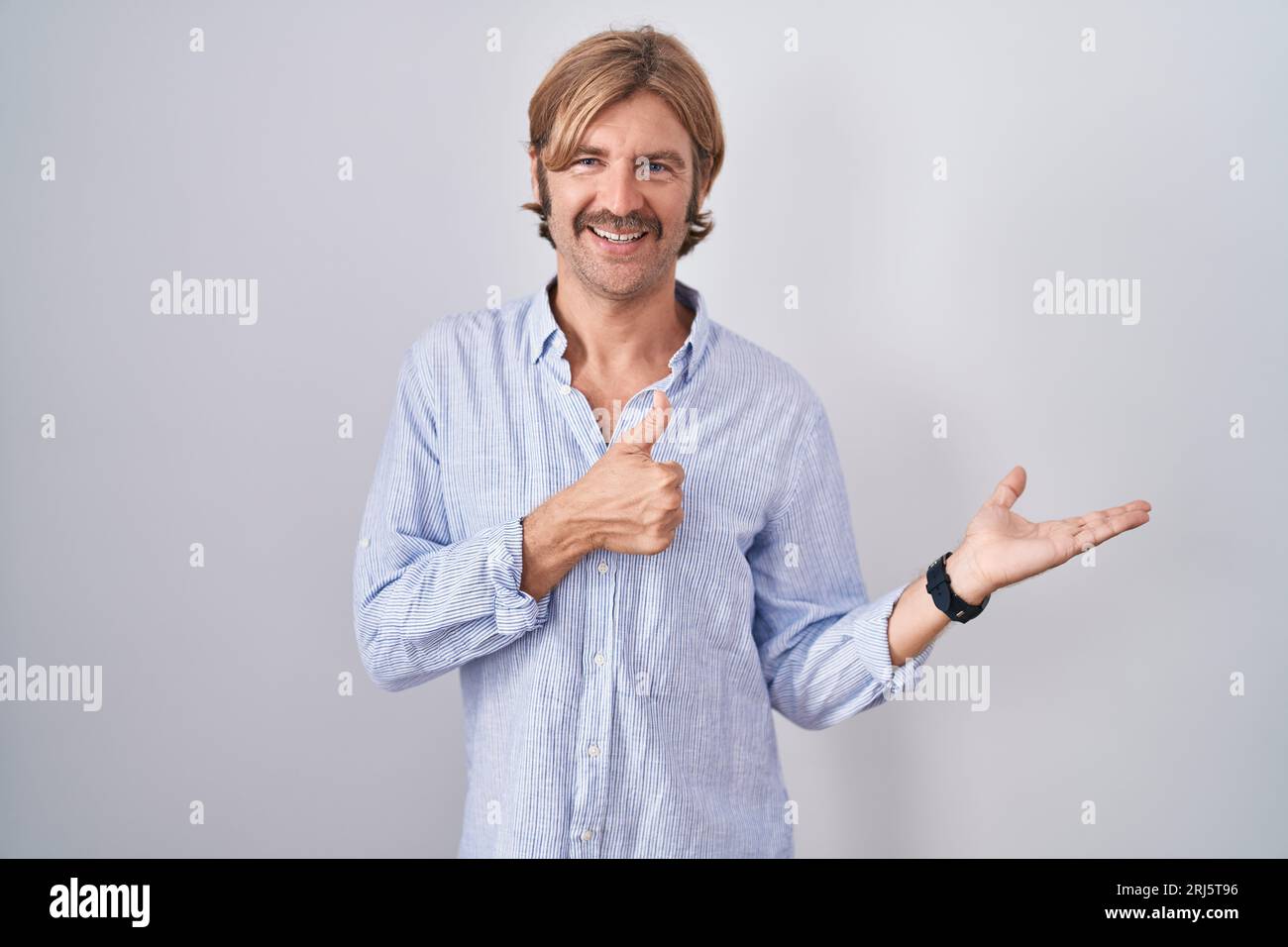 Caucasian man with mustache standing over white background showing palm ...