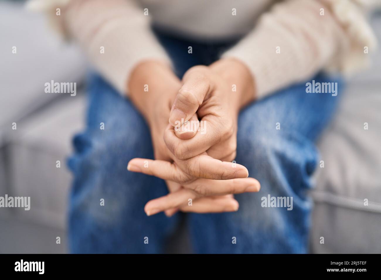 Young chinese woman sitting on sofa with hands together at home Stock ...