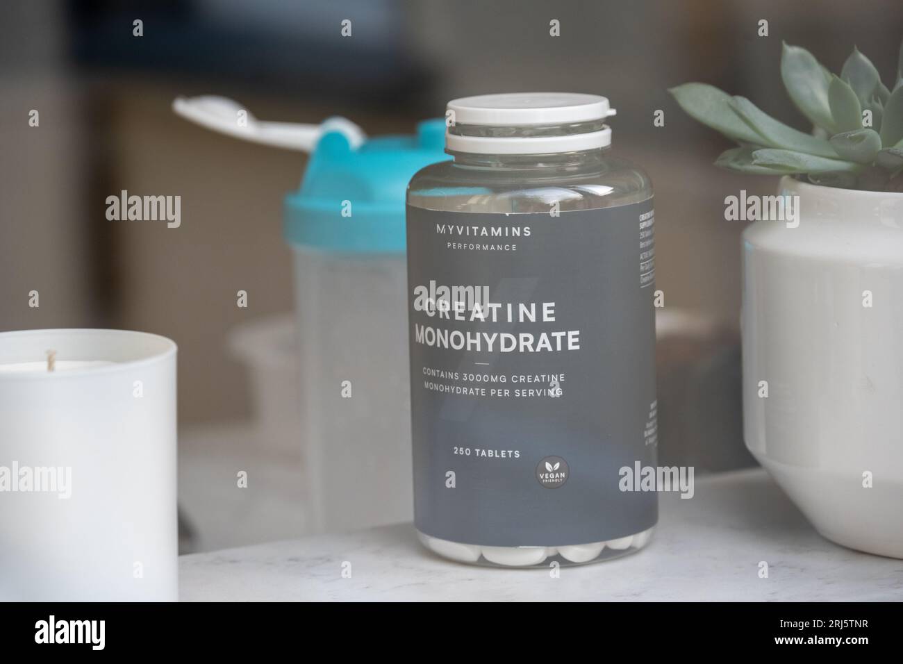 A white container of creatine monohydrate supplement next to a green ...