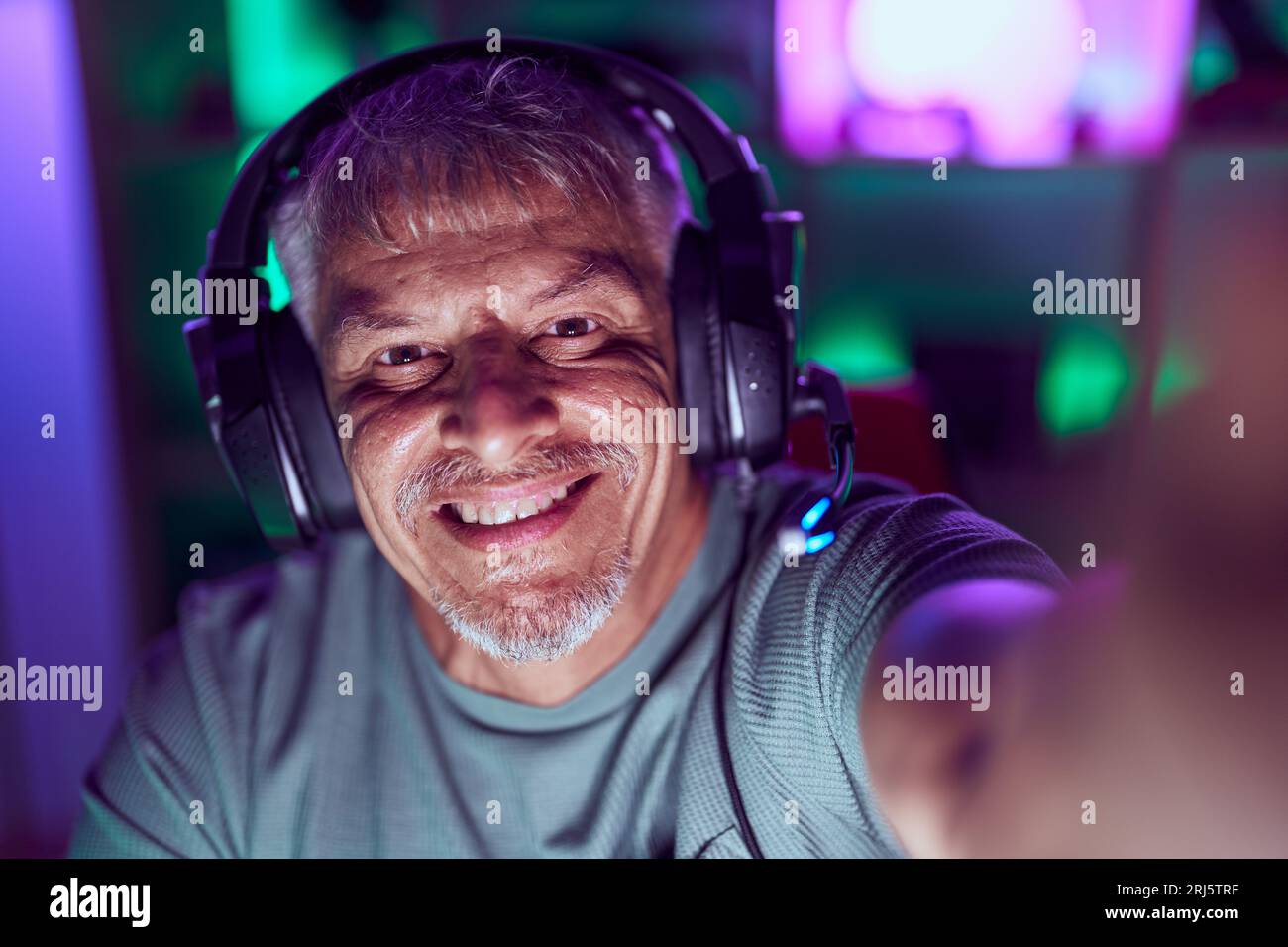 Middle age grey-haired man streamer make selfie by camera at gaming ...