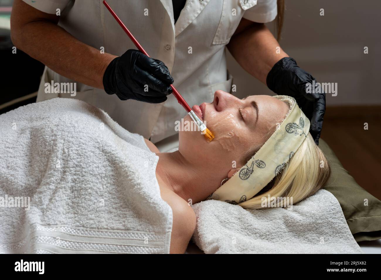 A female aesthetician is performing a facial treatment on a female ...
