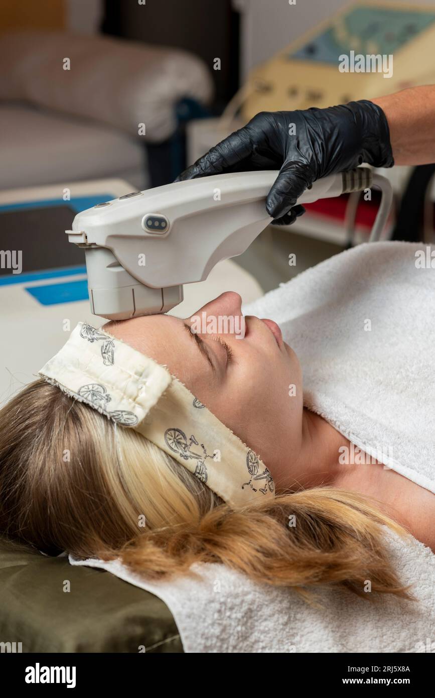 A female aesthetician is performing a facial treatment on a female ...