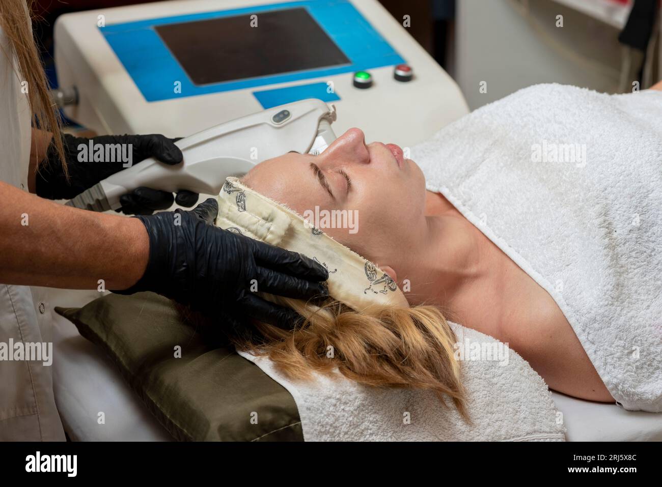 A female aesthetician is performing a facial treatment on a female ...