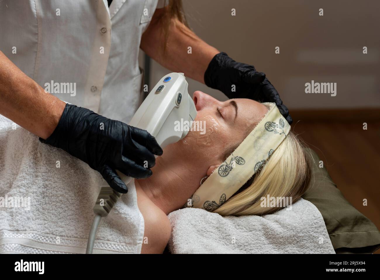 A female aesthetician is performing a facial treatment on a female ...
