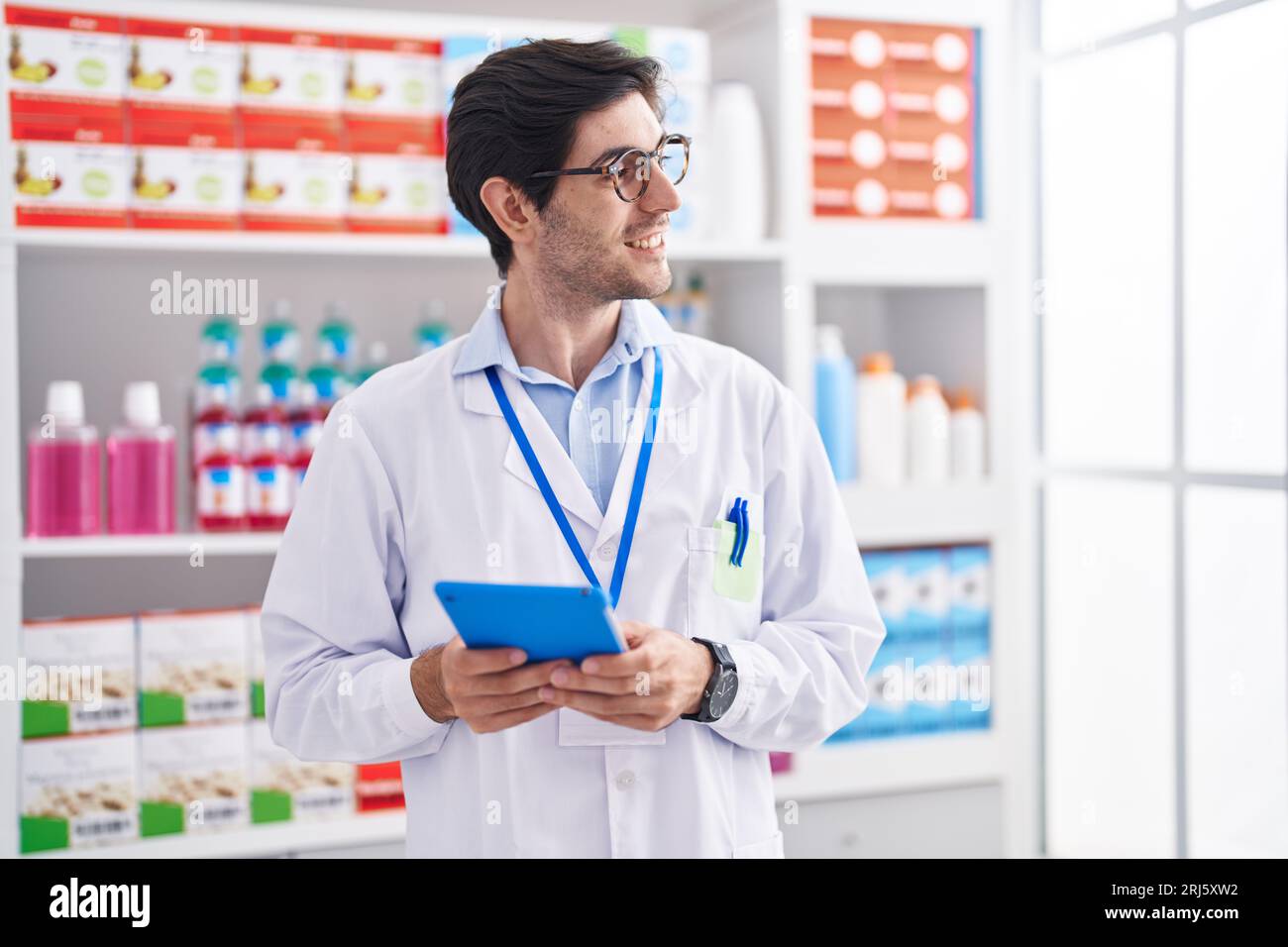 Young hispanic man pharmacist using touchpad working at pharmacy Stock ...