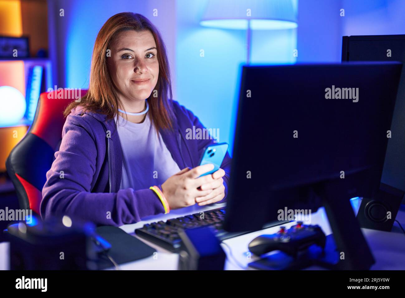 Young beautiful plus size woman streamer using computer and smartphone ...