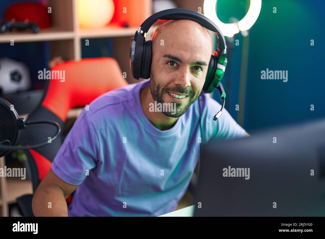 Young bald man streamer playing video game using computer at gaming ...