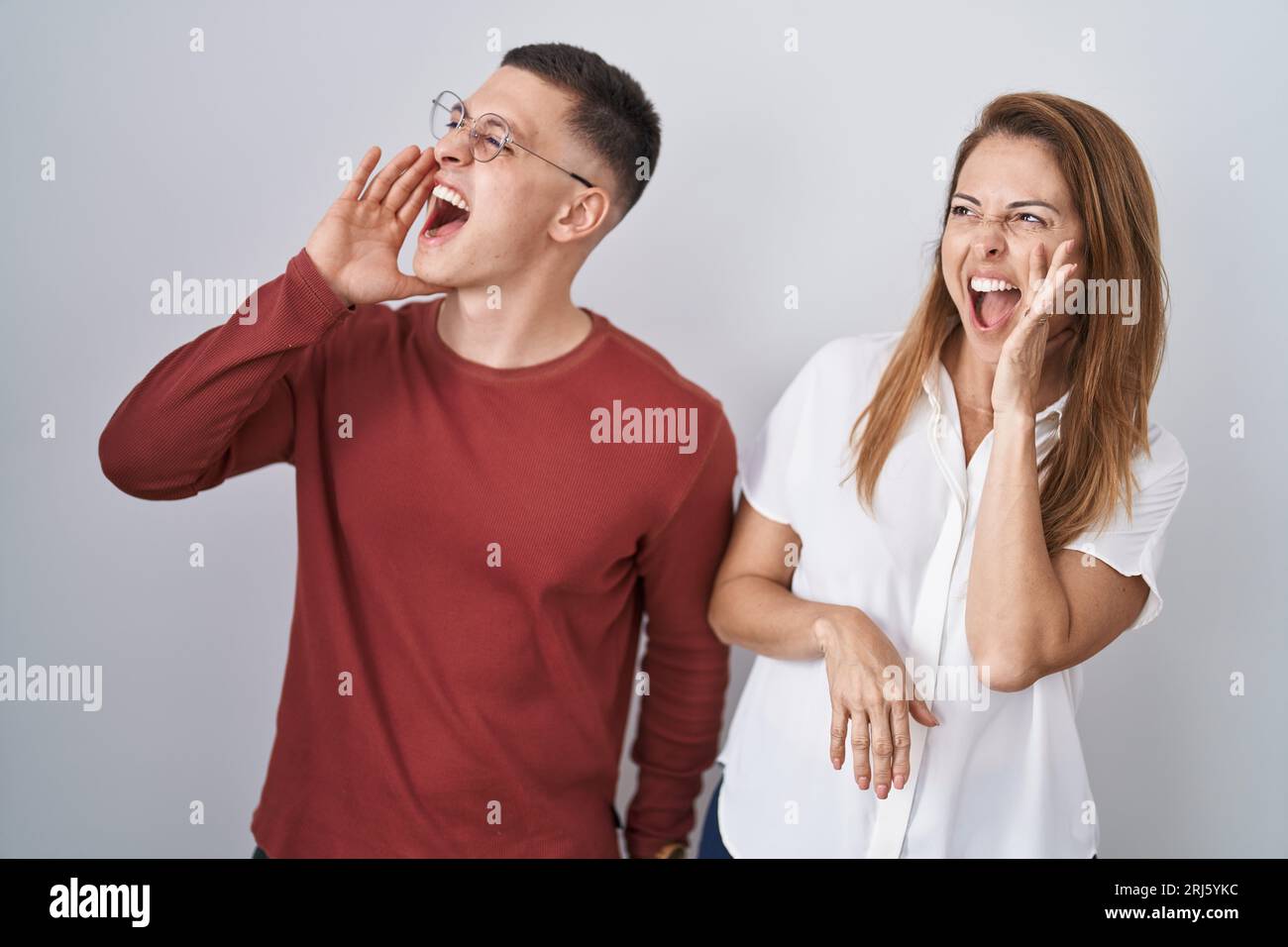 Mother and son standing together over isolated background shouting and ...