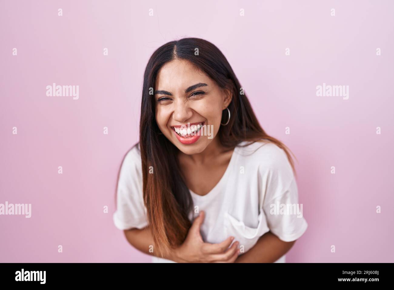 Young arab woman standing over pink background smiling and laughing ...