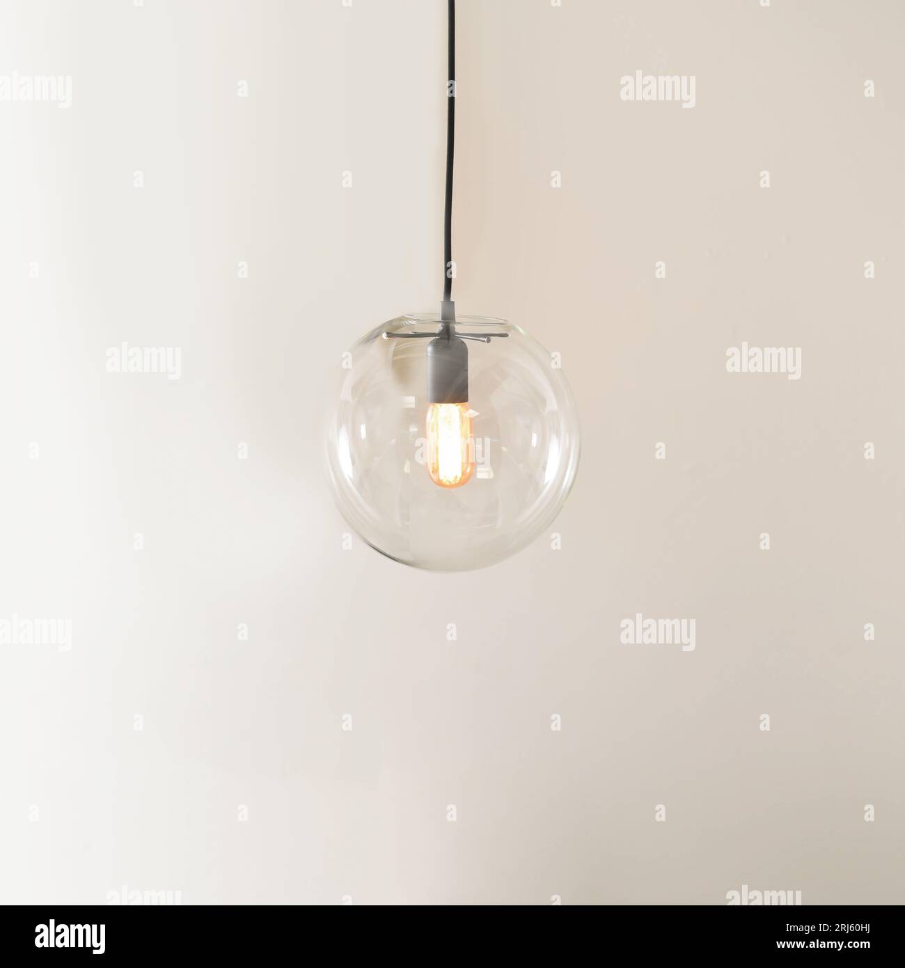 A contemporary, wire-suspended light fixture featuring a spherical ...