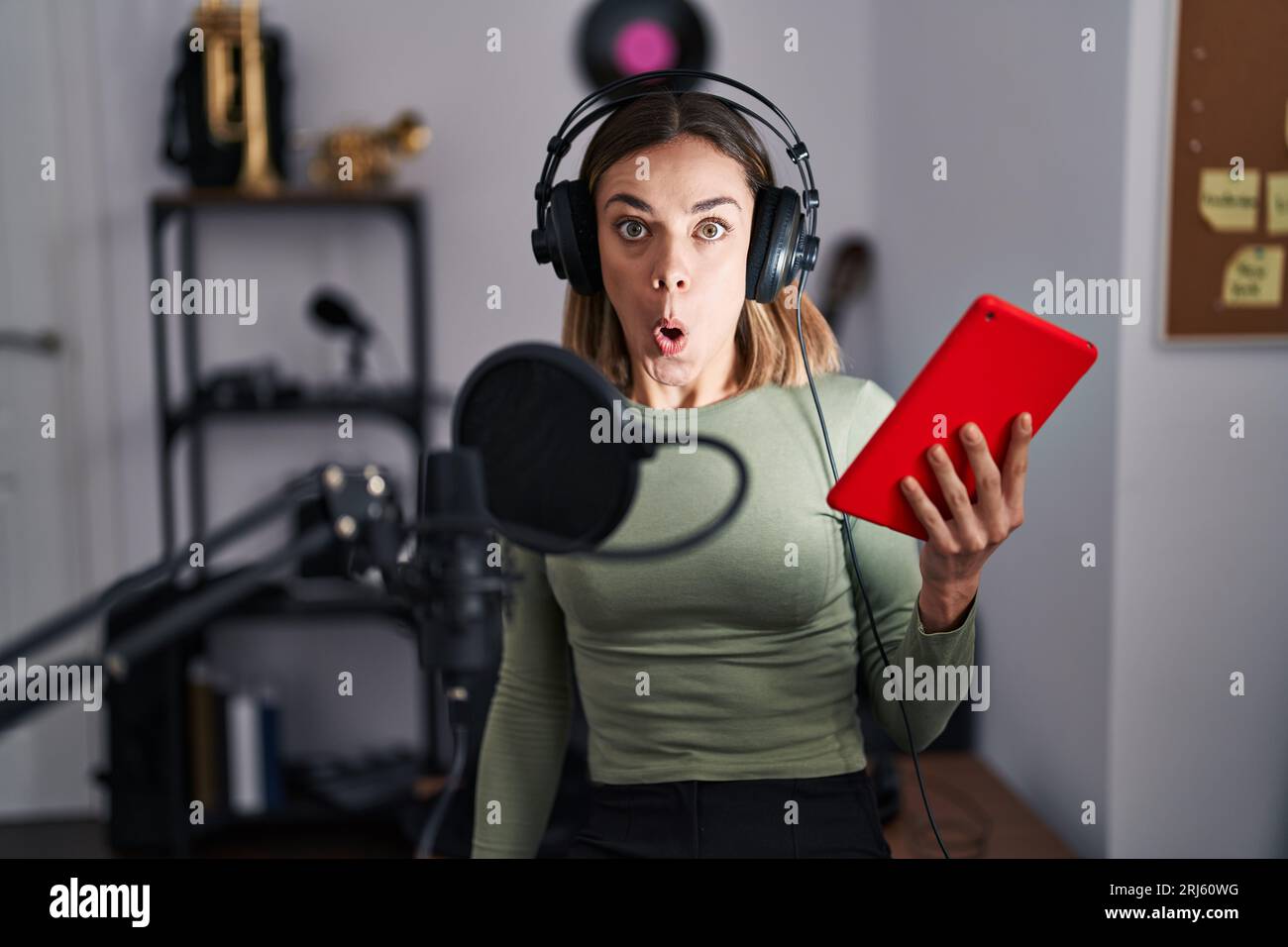 Hispanic woman singing song using microphone and tablet scared and ...
