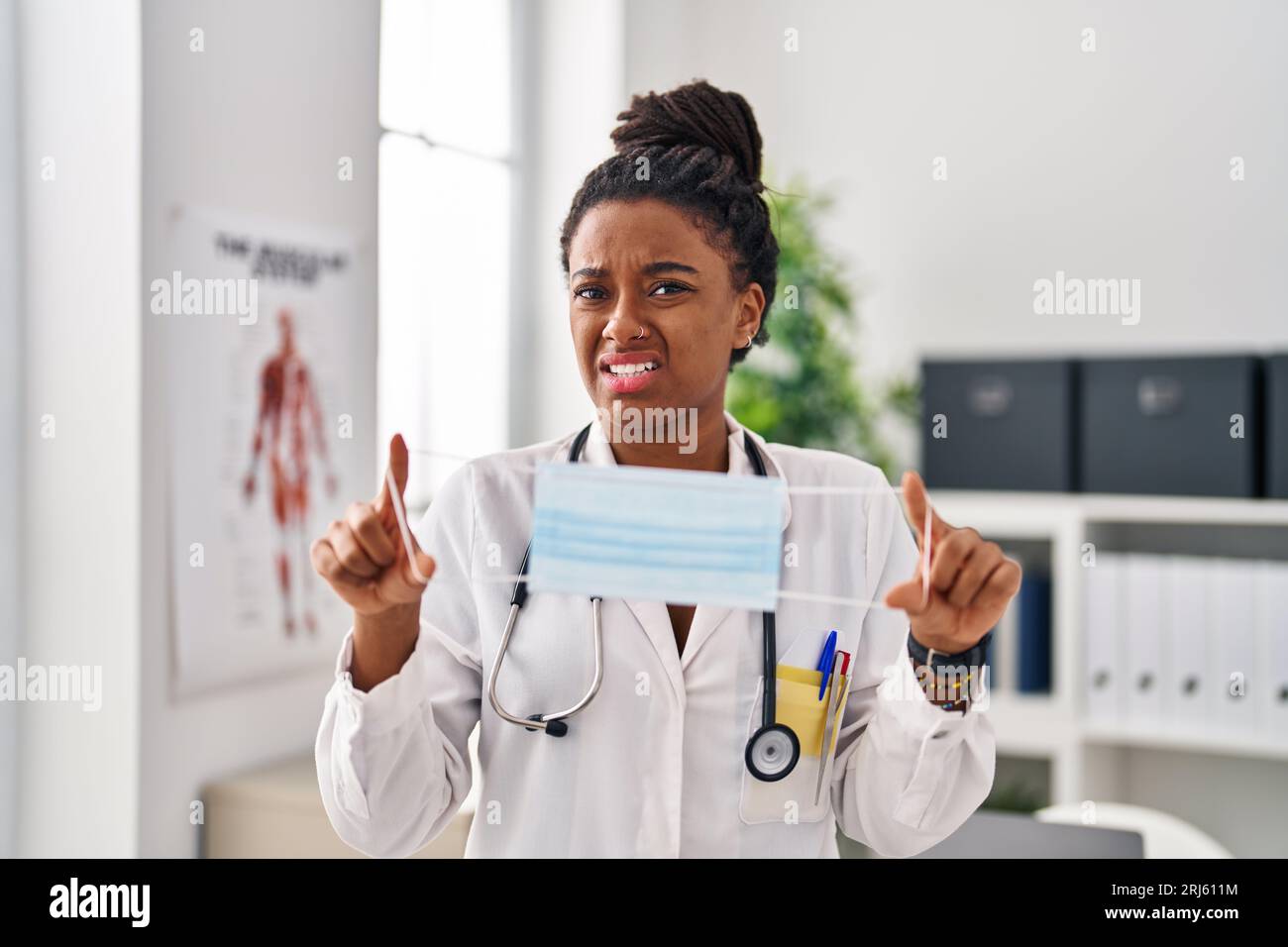 Young african american with braids wearing doctor uniform holding ...