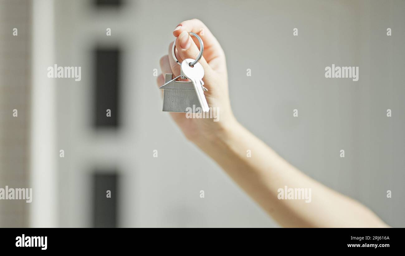 Young blonde woman real state agent holding keys of new home at street ...