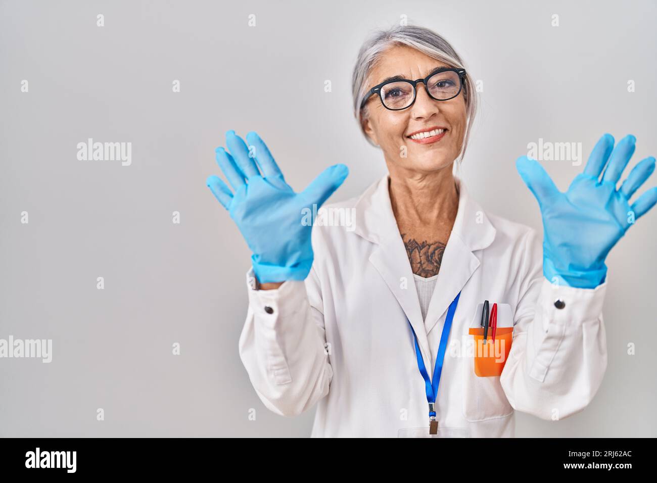 Middle age woman with grey hair wearing scientist robe showing and ...