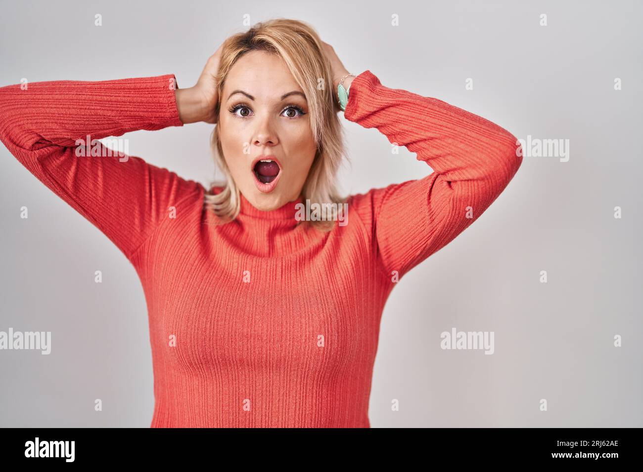 Blonde woman standing over isolated background crazy and scared with ...