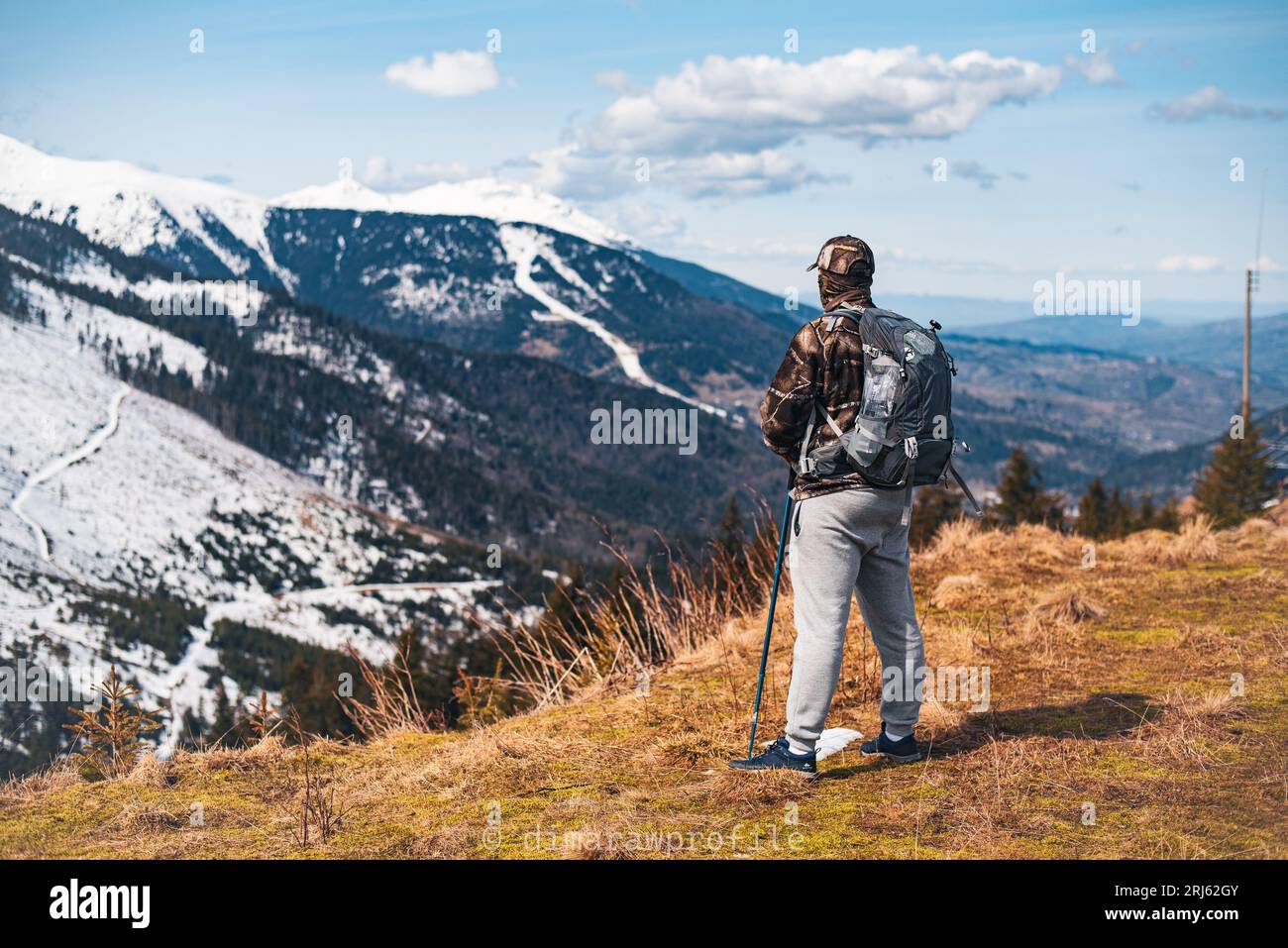 A man standing atop a mountain peak, looking out at the breathtaking ...