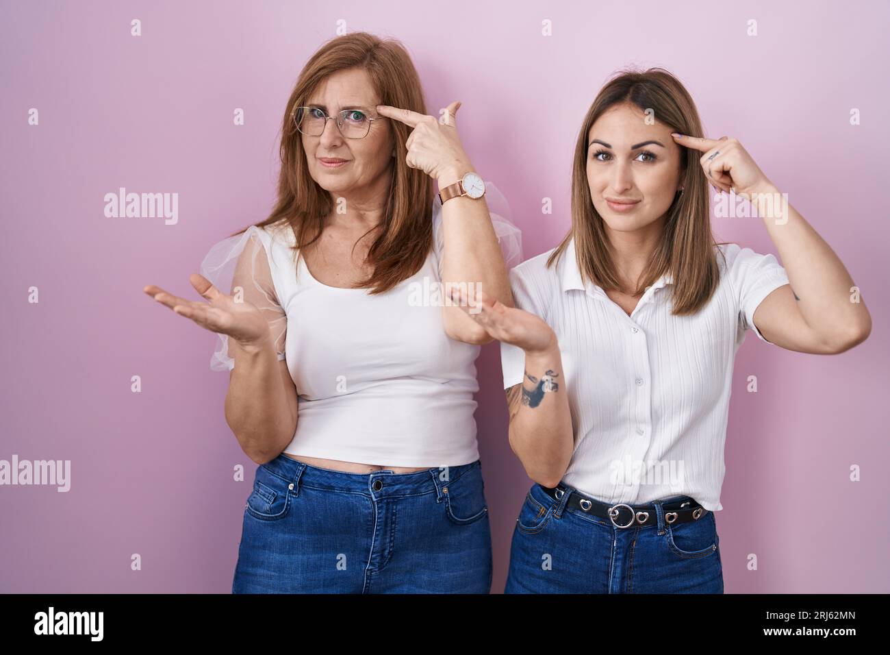 Hispanic mother and daughter wearing casual white t shirt over pink ...