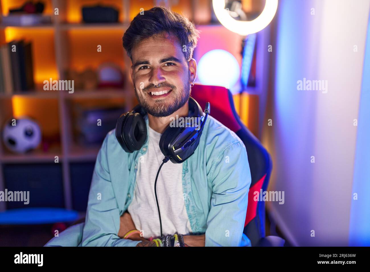 Young hispanic man streamer smiling confident sitting with arms crossed ...