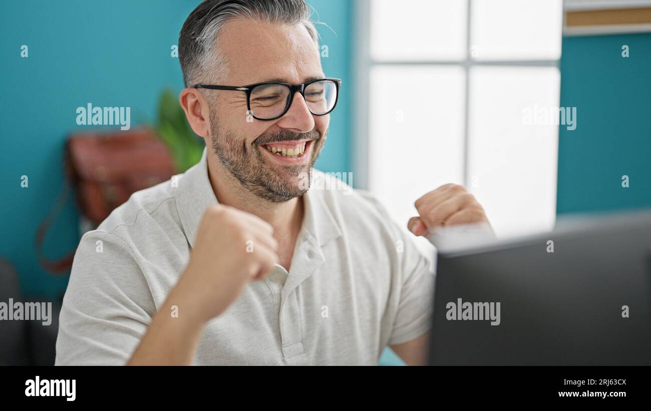 Grey-haired man business worker using computer celebrating at the ...