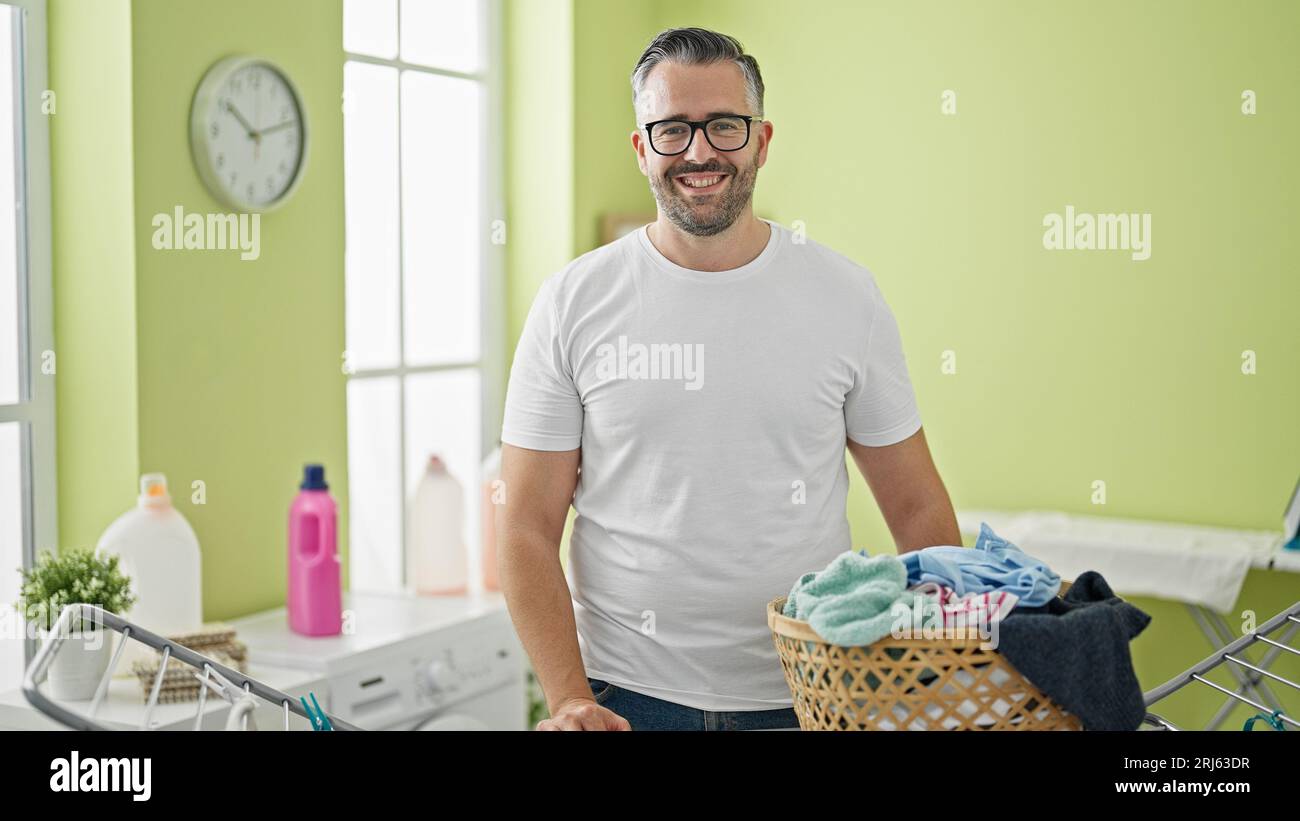 Grey-haired man smiling confident standing by clothesline at laundry ...