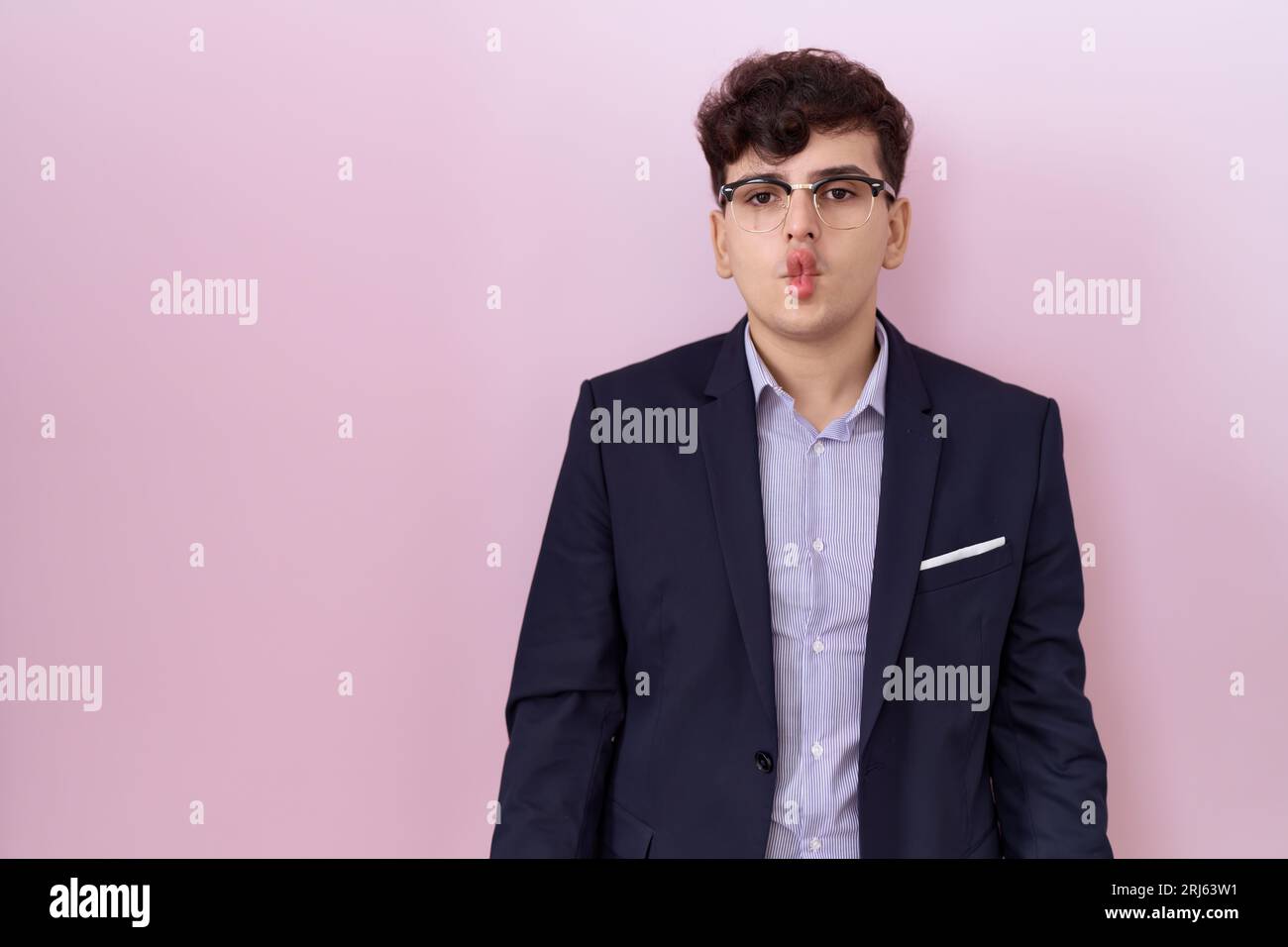 Young non binary man with beard wearing suit and tie making fish face ...