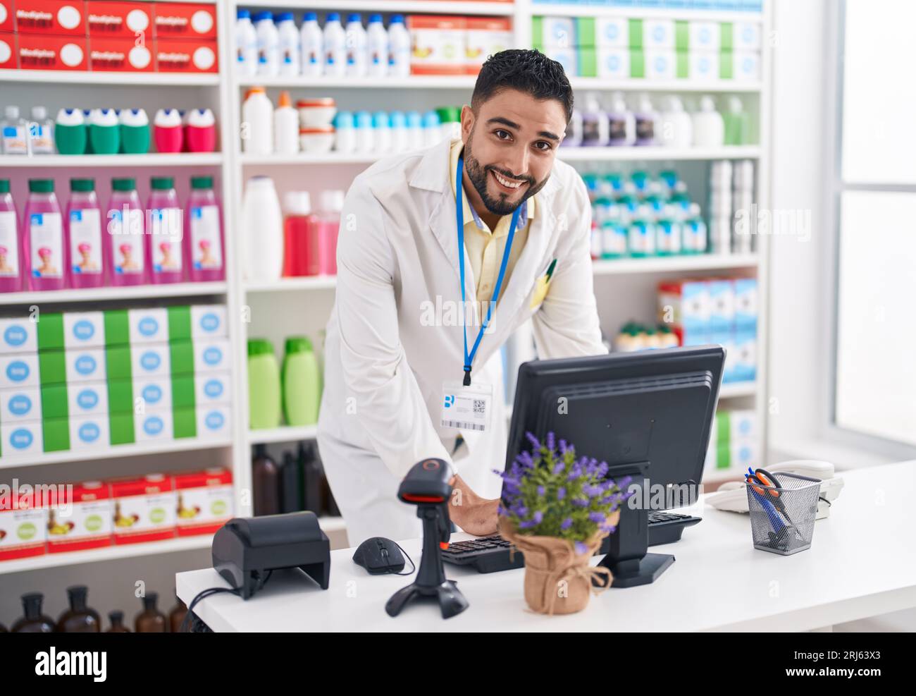 Young arab man pharmacist smiling confident using computer at pharmacy ...