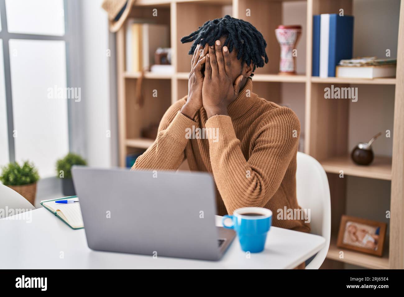 Young african man with dreadlocks working using computer laptop with ...