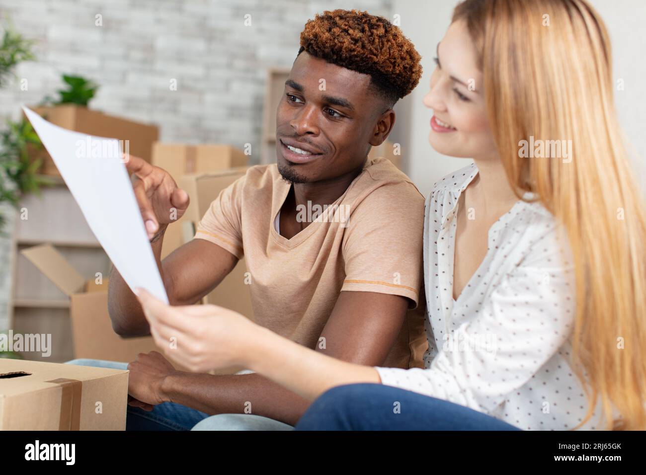 couple surrounded by boxes looking at paper Stock Photo - Alamy