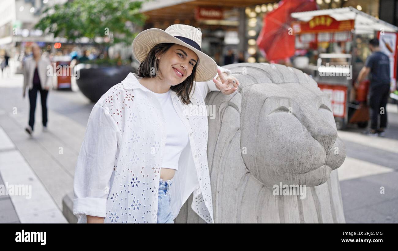 Beautiful young hispanic woman standing with famous lion statue in the ...