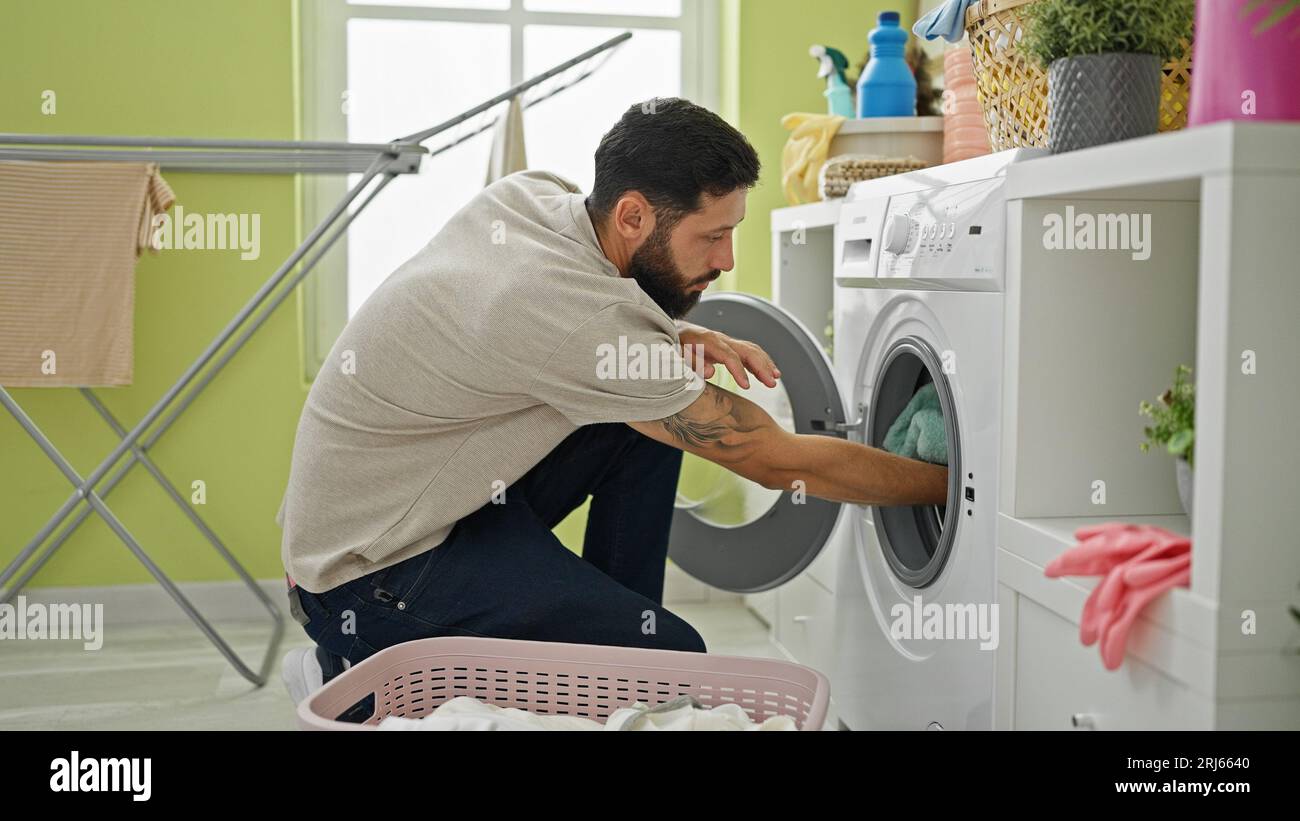 Young hispanic man washing clothes at laundry room Stock Photo - Alamy