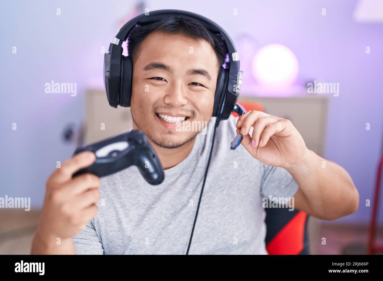 Young chinese man streamer playing video game using joystick at gaming ...