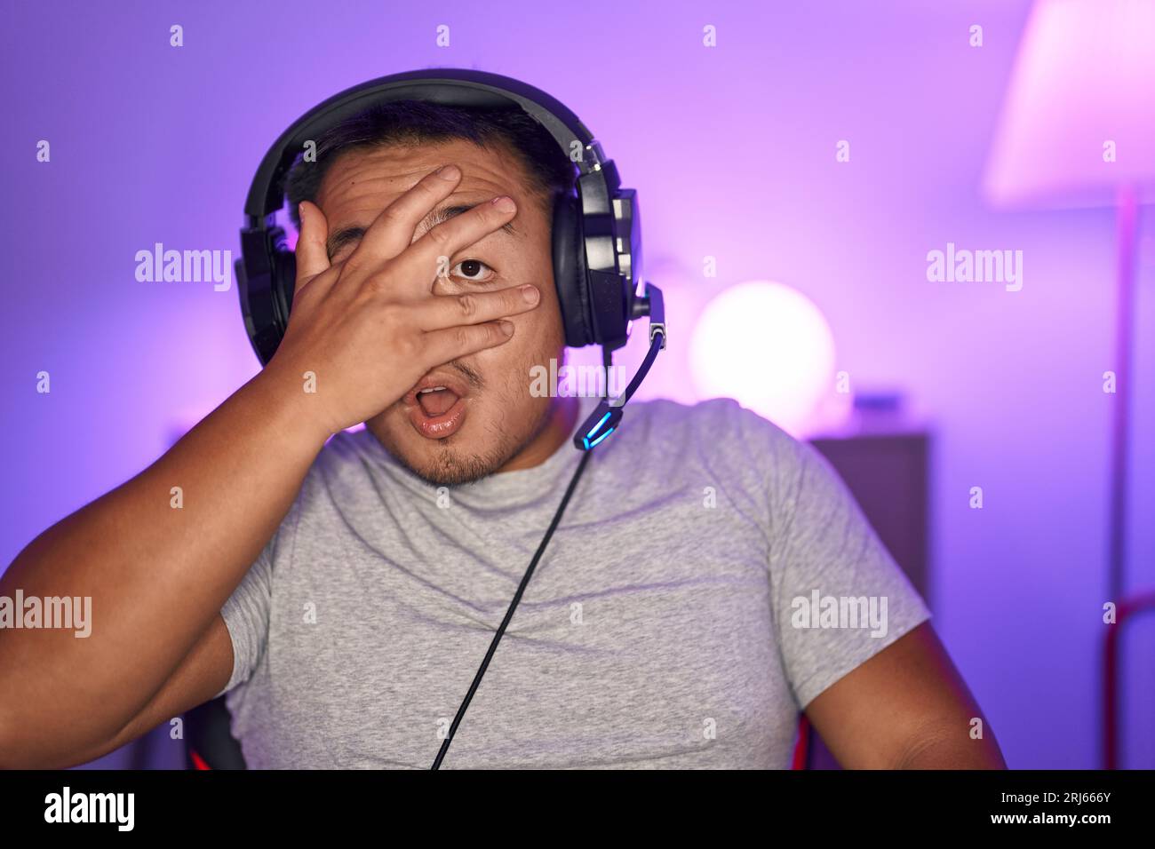 Chinese young man playing video games wearing headphones peeking in ...