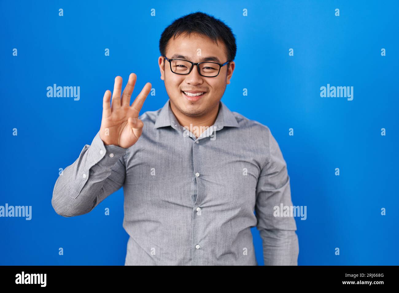 Young chinese man standing over blue background showing and pointing up ...
