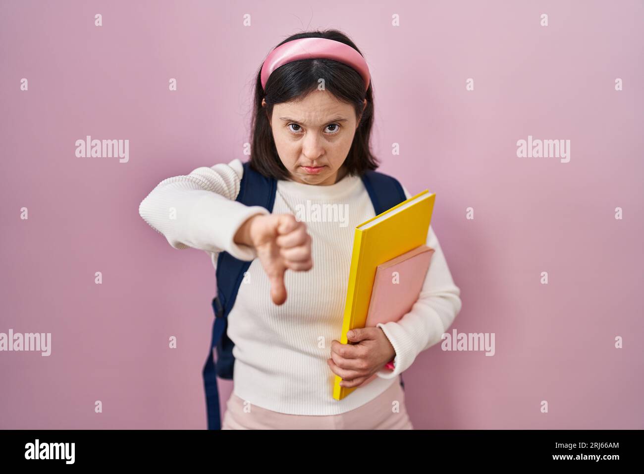Woman with down syndrome wearing student backpack and holding books ...