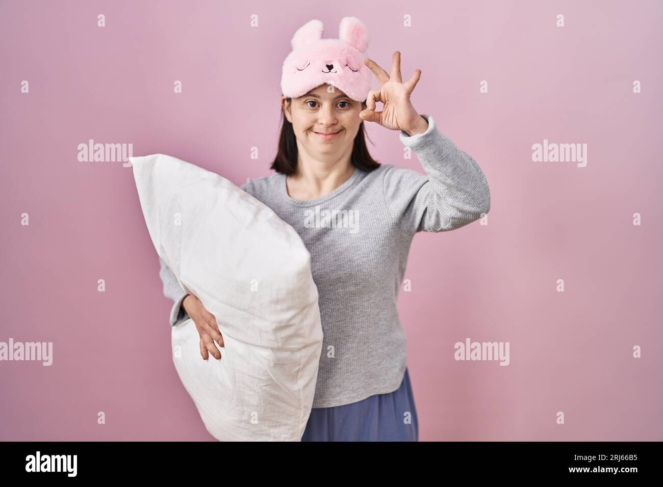 Woman with down syndrome wearing sleeping mask hugging pillow smiling ...