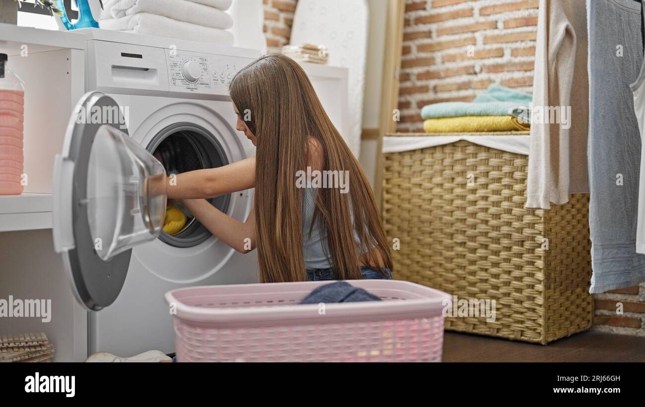 Young beautiful girl washing clothes at laundry room Stock Photo - Alamy