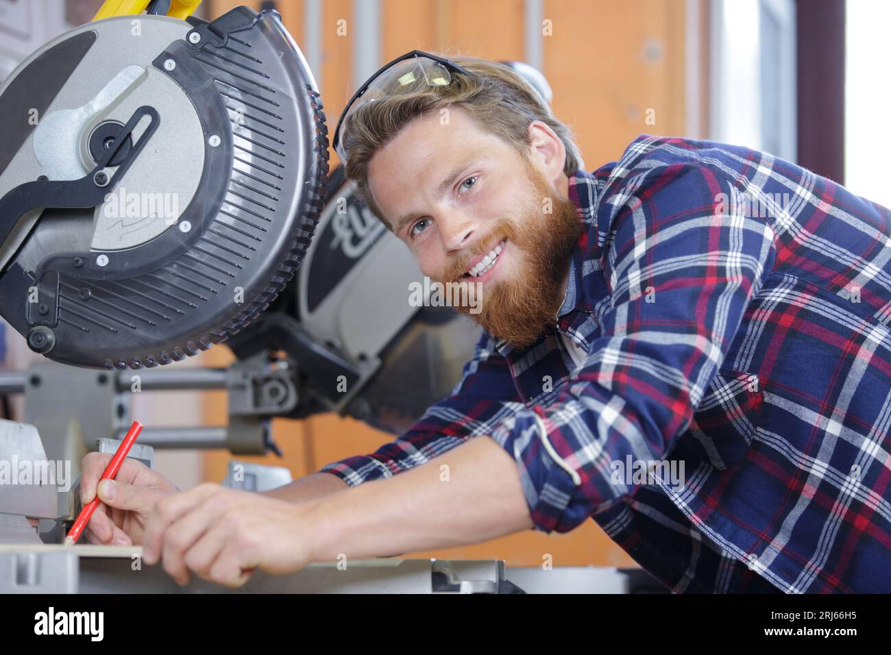 glad diligent man wearing protective workwear operating circular saw ...