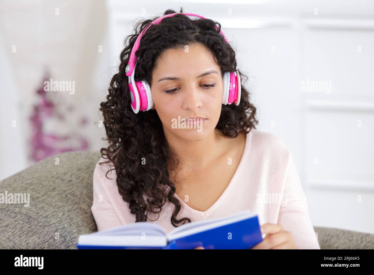 young female listening music while reading a book Stock Photo - Alamy