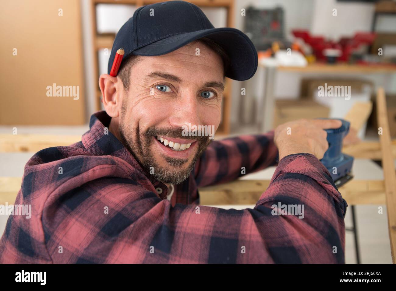 happy workman cutting wooden planks in workshop Stock Photo - Alamy