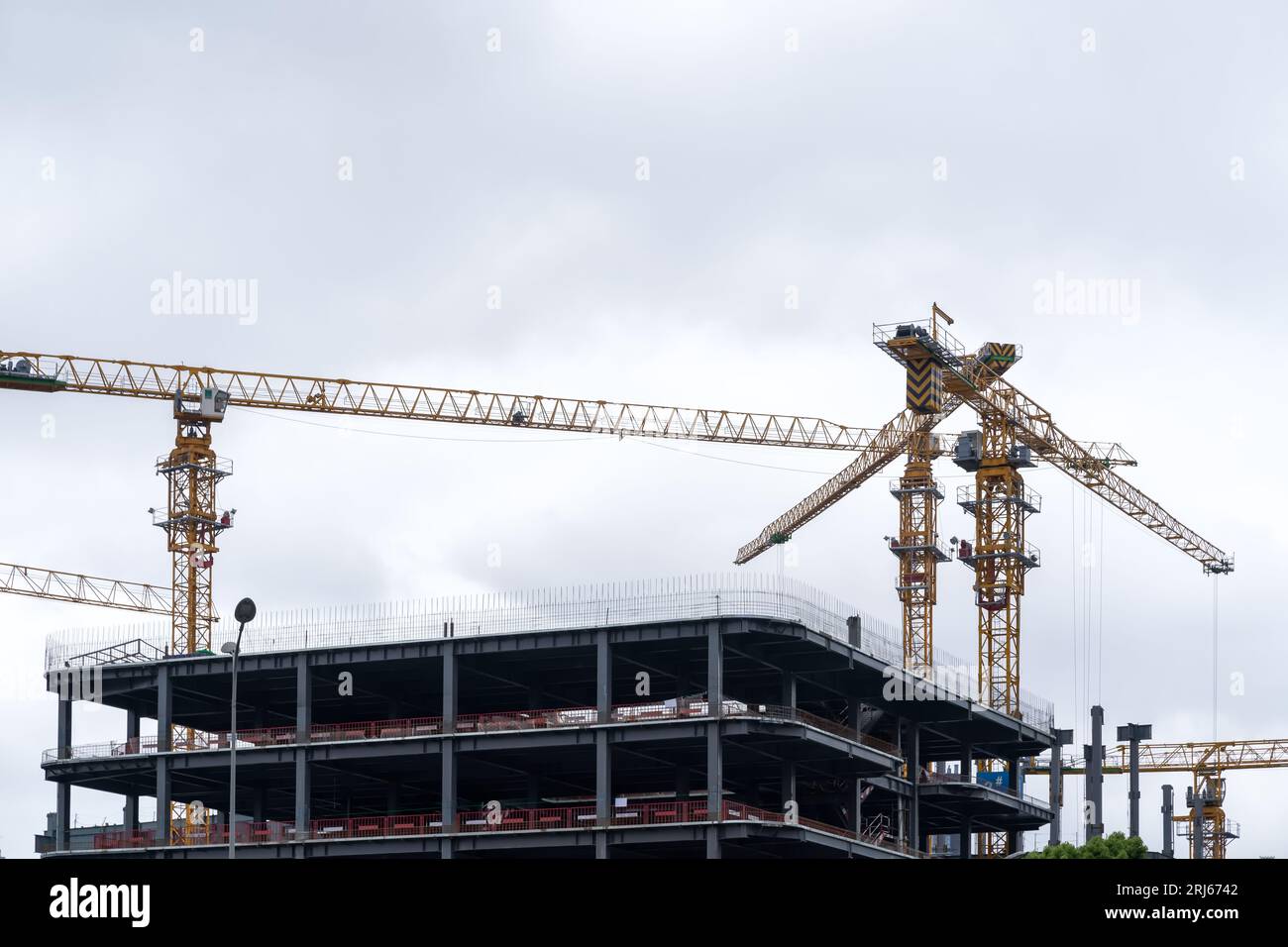 A skyline of a city with multiple construction cranes alongside a tall ...