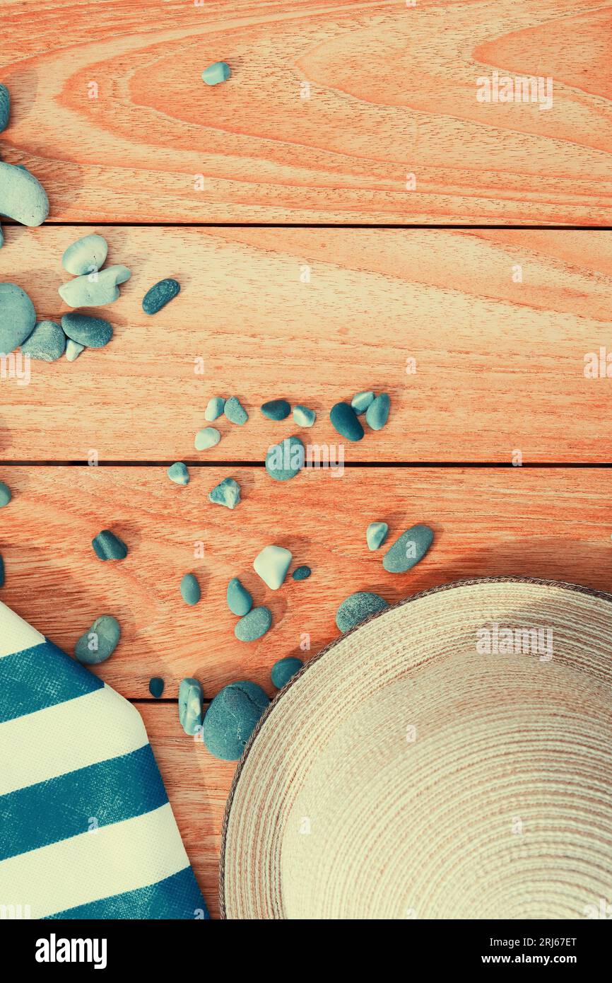 Straw sun hat, beach striped bag and pebbles on the wooden table. Sea ...