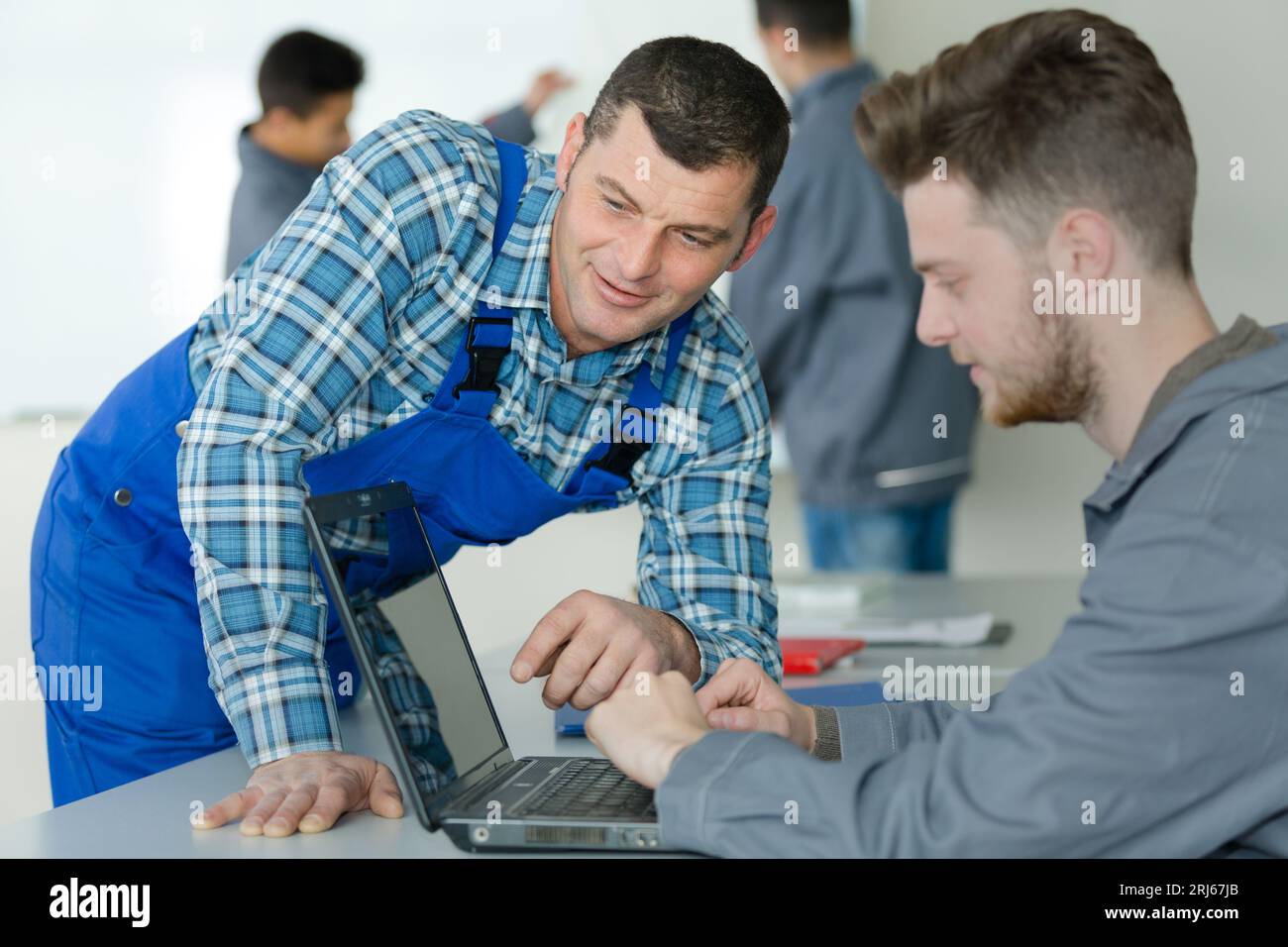 teacher helping student using laptop Stock Photo - Alamy