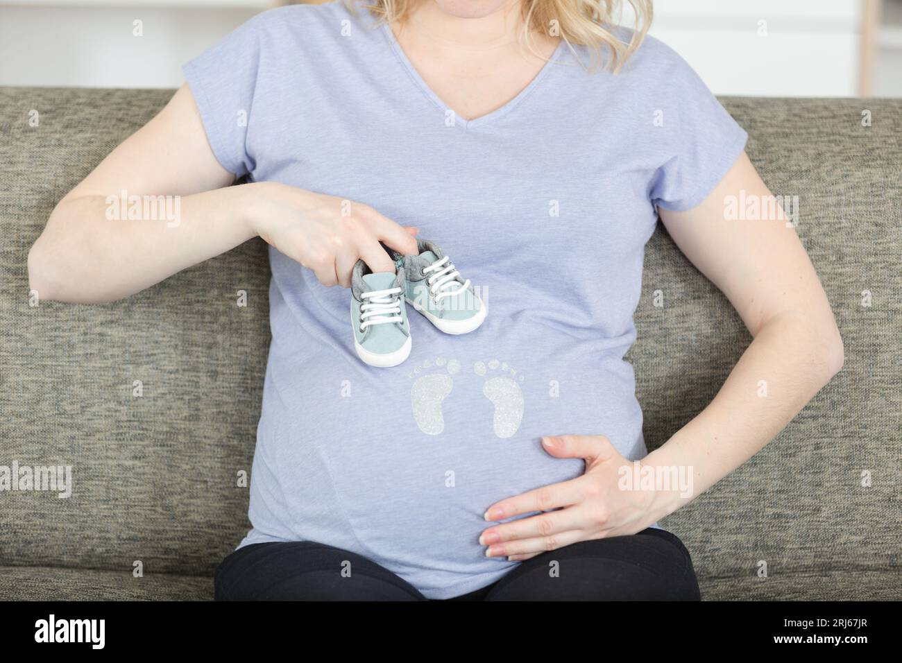 pregnant lady holding lottle boots next to her bump Stock Photo - Alamy