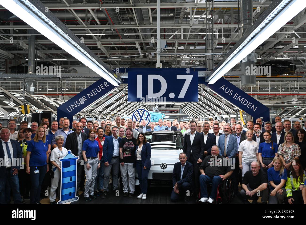 Emden, Germany. 21st Aug, 2023. VW employees stand next to one of the ...