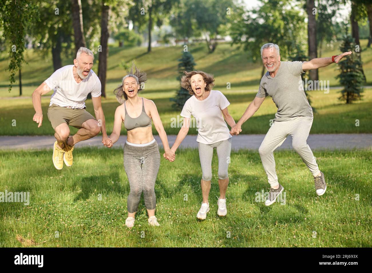 Group of healthy runners team jumping in the air at city park during ...