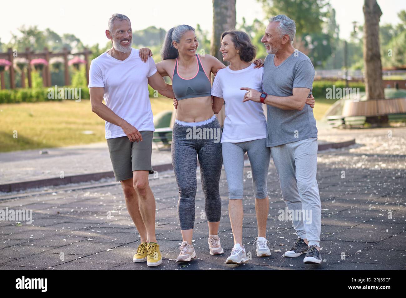Mature people standing together in park hugging smiling, healthy ...
