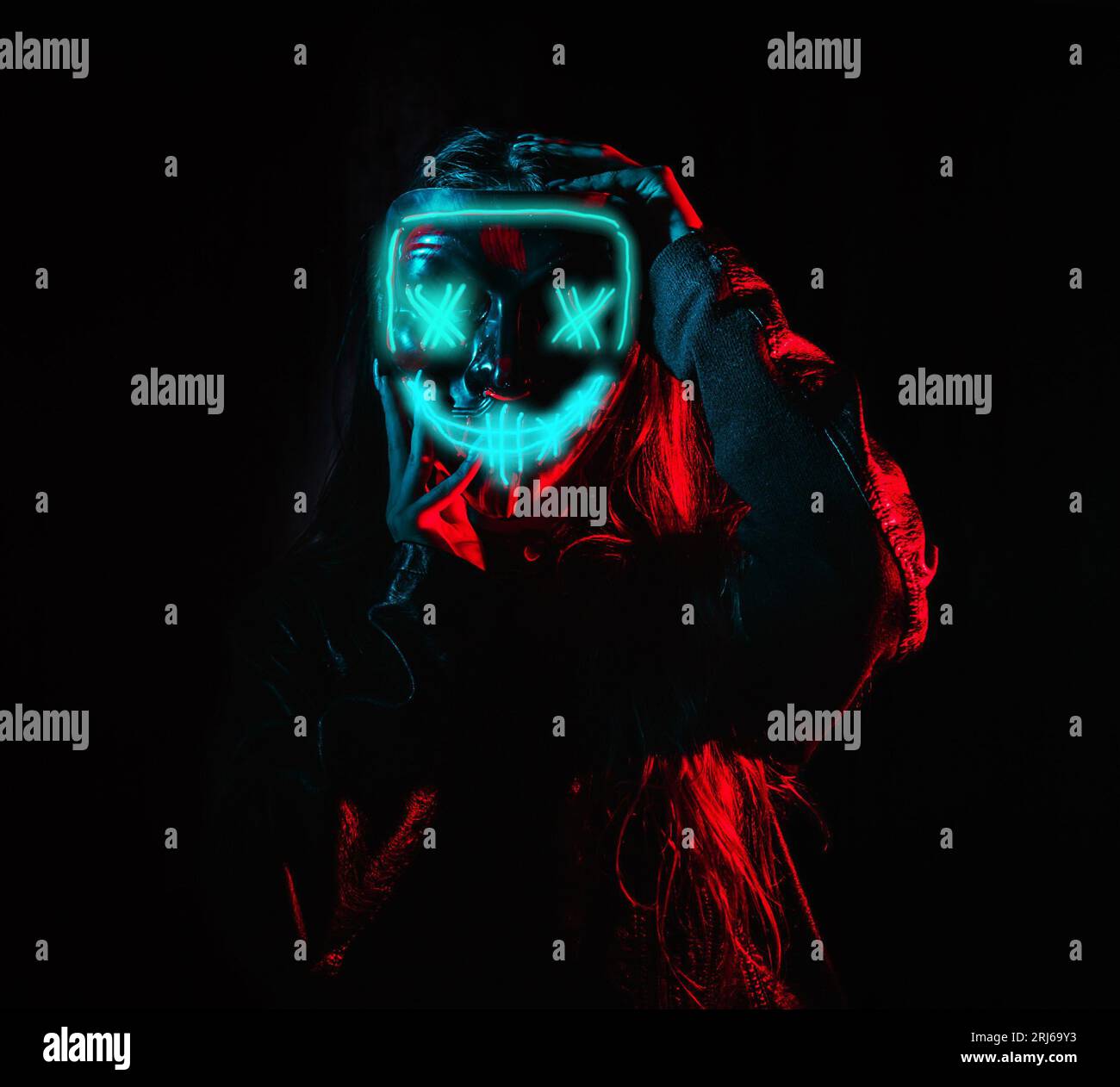 A crazy girl with her fingers on her ominous neon mask striking a pose ...